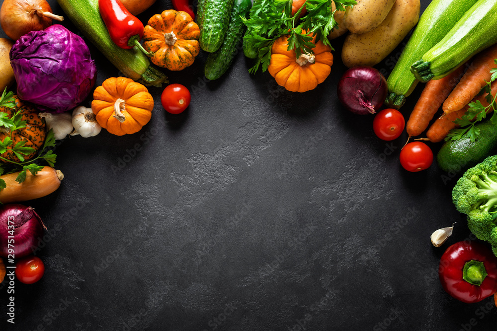 Culinary background with fresh raw vegetables on a black kitchen table ...