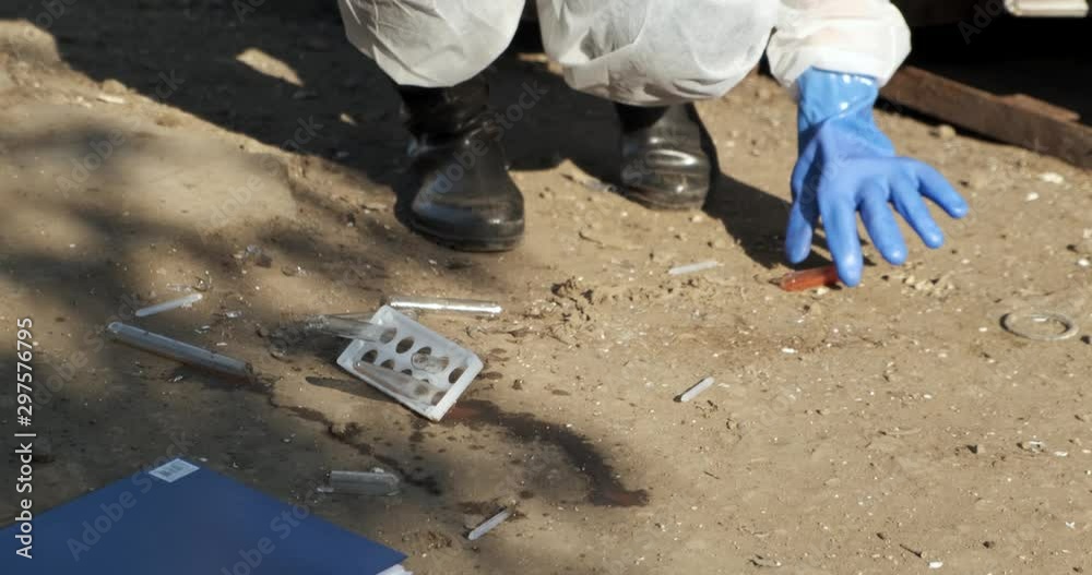 Scientist in chemical protection suit collects tubes from ground with ...