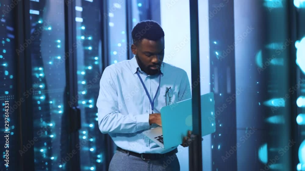 African IT engineer using notebook inspecting super computers network ...