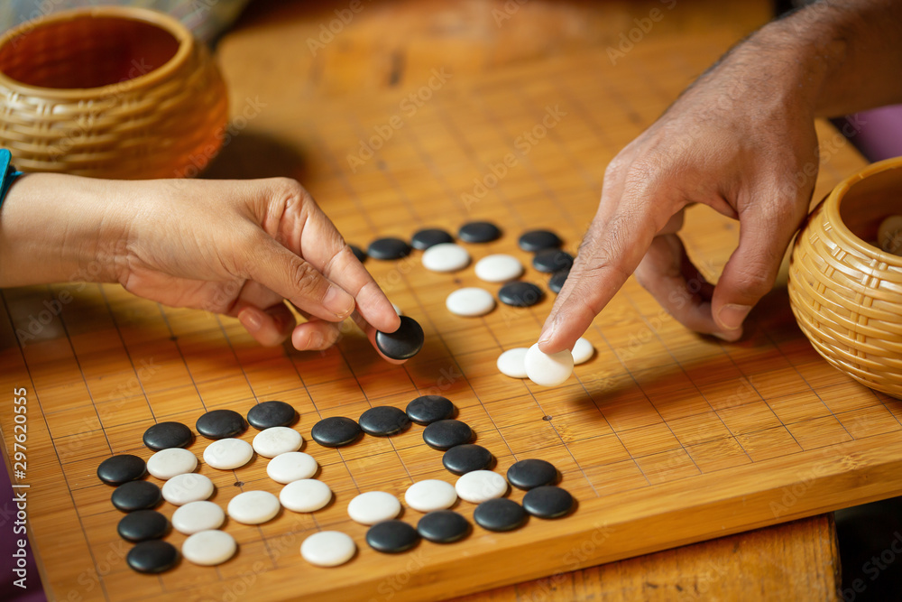 Go board game playing. A competitor is placing a marble piece on a Go ...