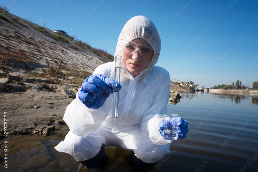 Ecologist taking water sample from the river with test tube for ...