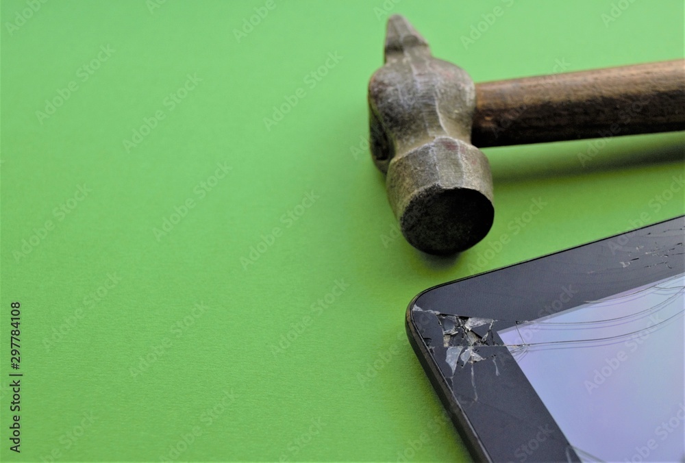 An old hammer with a worn wooden lies next to the tablet with a broken ...