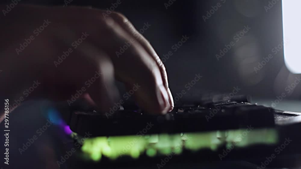 Programmer typing code on a backlit keyboard in a dark room, passionate ...