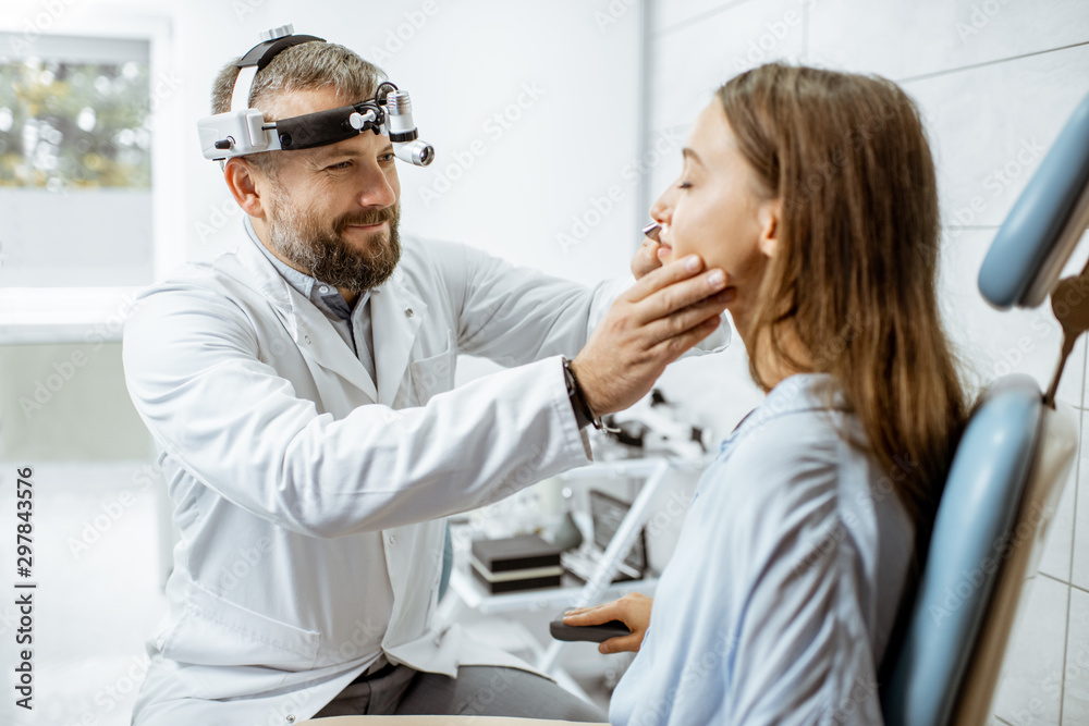 Senior otolaryngologist examining nose of a young patient during a ...