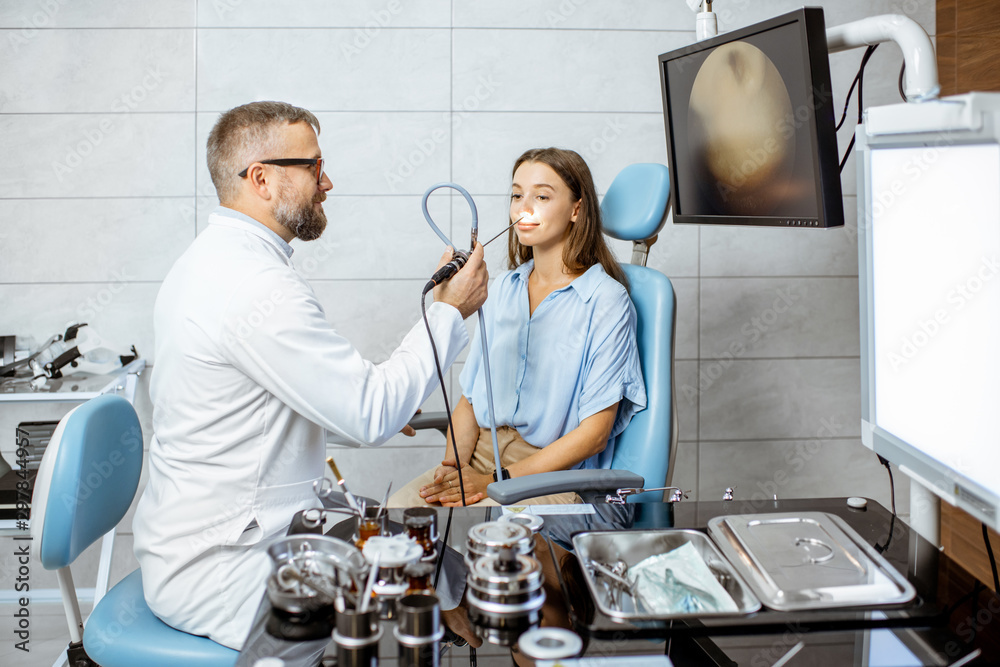 Senior otolaryngologist making endoscopic examination of a nose for a ...