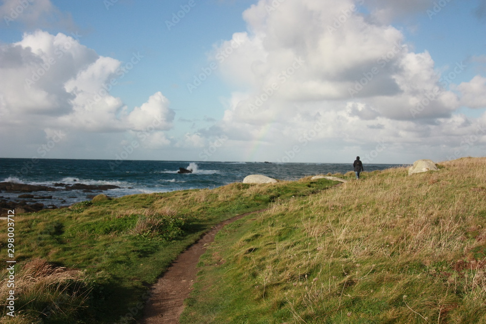 Personne se baladant au bord de mer sous le soleil et les nuages Stock ...