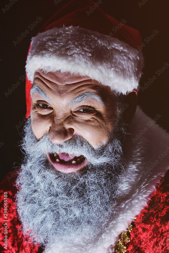 evil Santa Claus grimaces and scares a terrible face on a dark ...