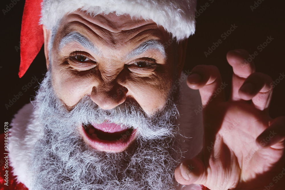 evil Santa Claus grimaces and scares a terrible face on a dark ...