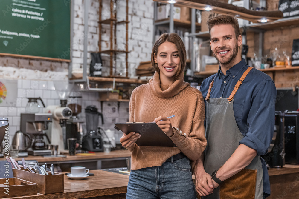 Small business smiling partners standing together at their coffee shop ...