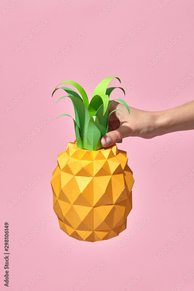 Paper whole pineapple with green leaves is holding a woman's hand on a ...