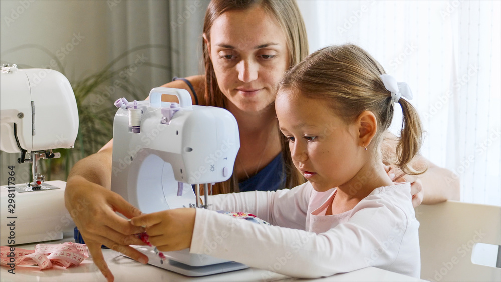 A girl is using a small sewing machine, a woman using a needle. A ...
