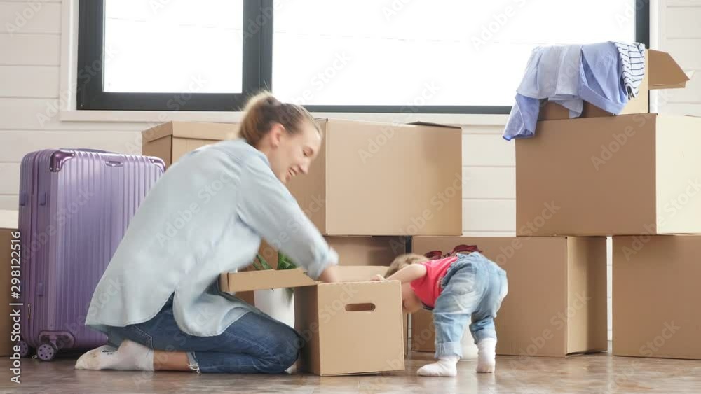 Little child looks in box. Background moving boxes and suit. Mother ...