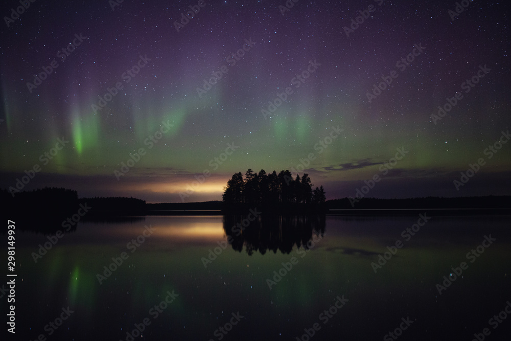 Northern lights spinning across the starry night sky over a lake ...