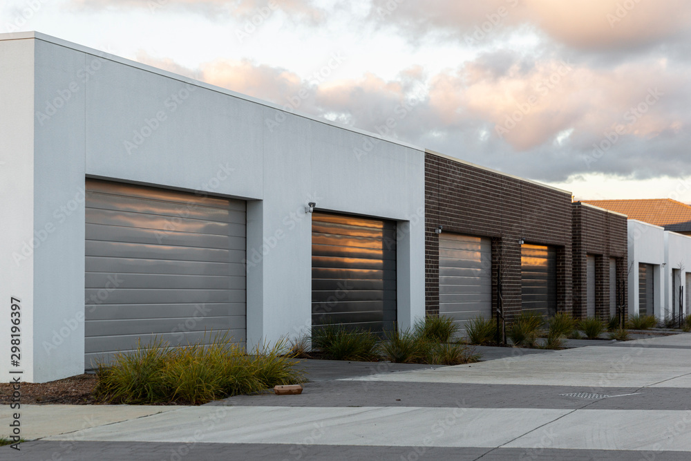 Modern car garages reflecting golden afternoon light in suburban area ...