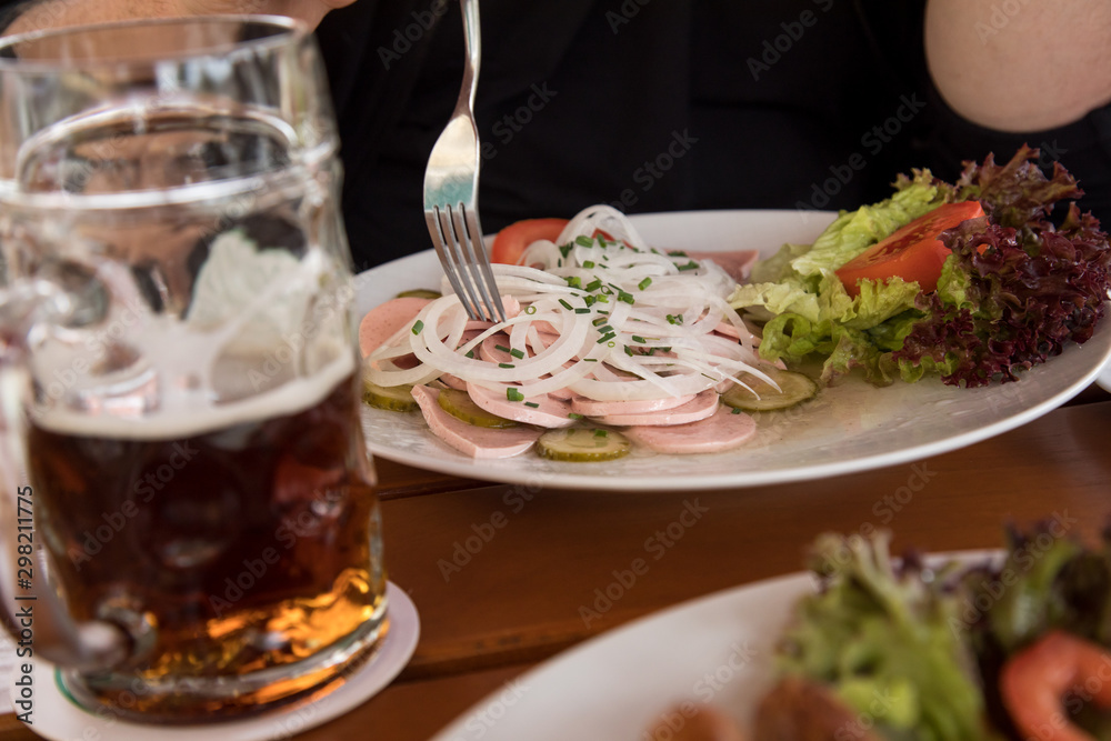 Mann mit dunklen Bier und Bayrischen Wurstsalat aus Stadtwurst, Zwiebel ...