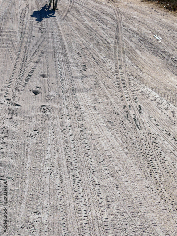 Sandy road. Traces of different tires printed in the sand. Human steps ...