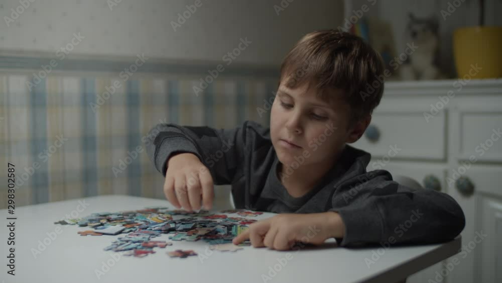 Vidéo Stock Autistic kid completing jigsaw puzzle on the table in slow ...