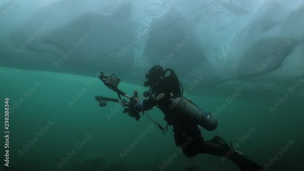Underwater cameraman technical diver with camera under ice in cold ...