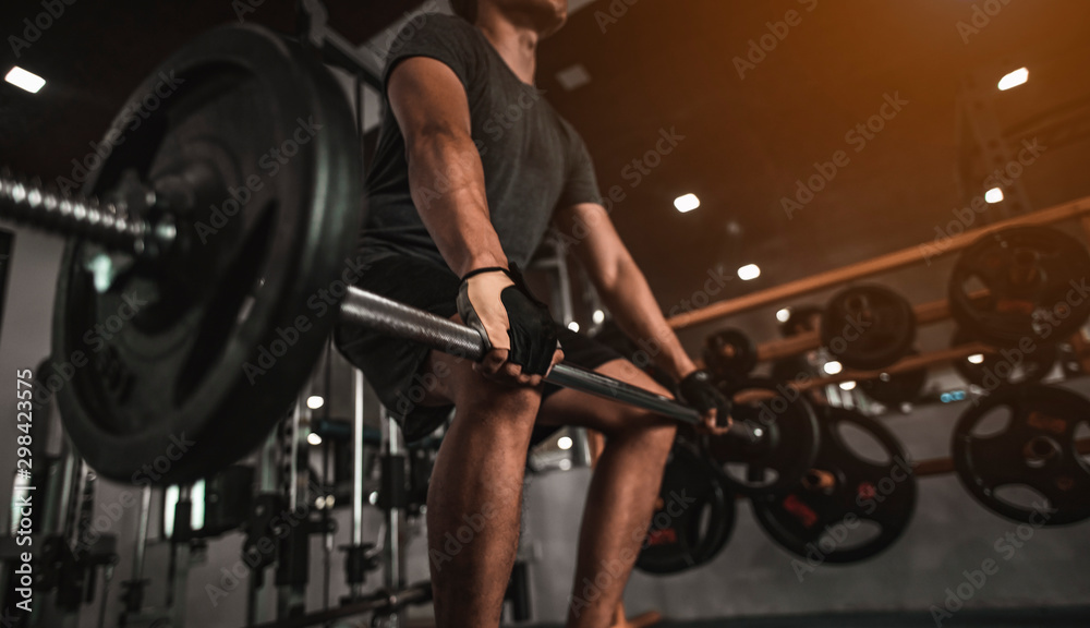 A side view of a young bodybuilder exercising in the gym, ready to lift ...