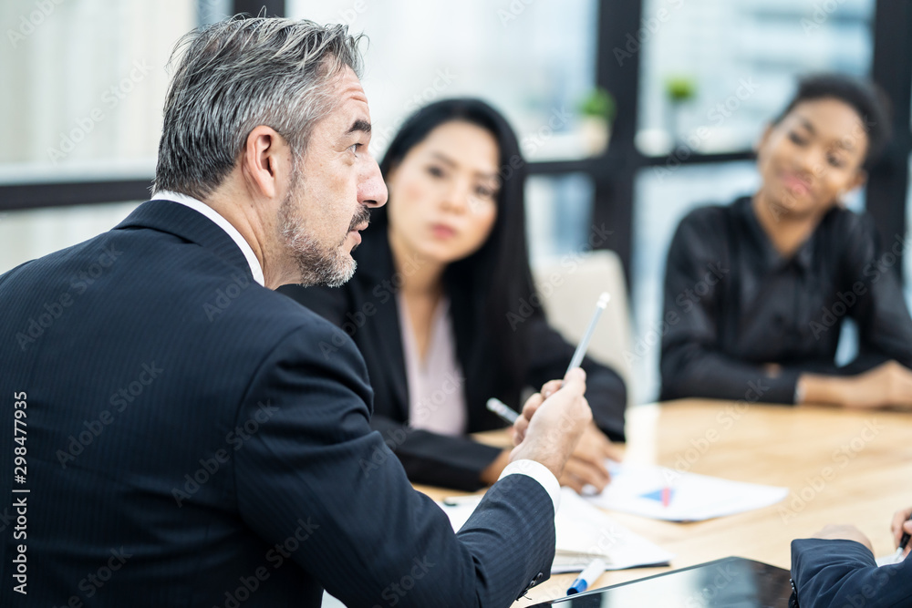 Caucasian serious boss explaining job in meeting room to employees in ...