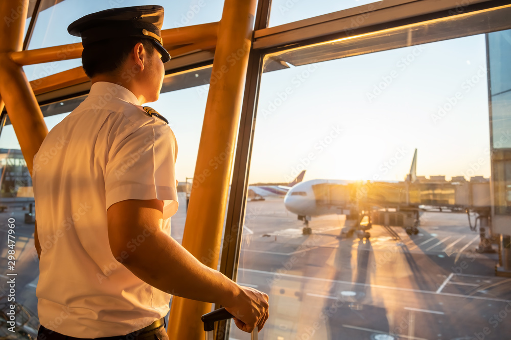 Pilot in uniform standing at boarding gate area in airport terminal, is ...