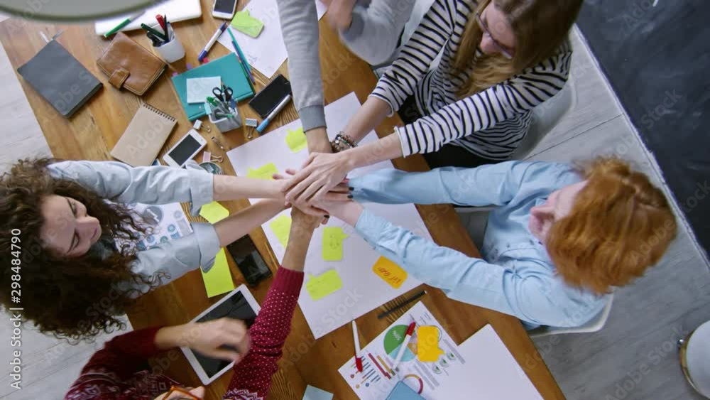 Zoom out top view of young creative business team huddling and then ...