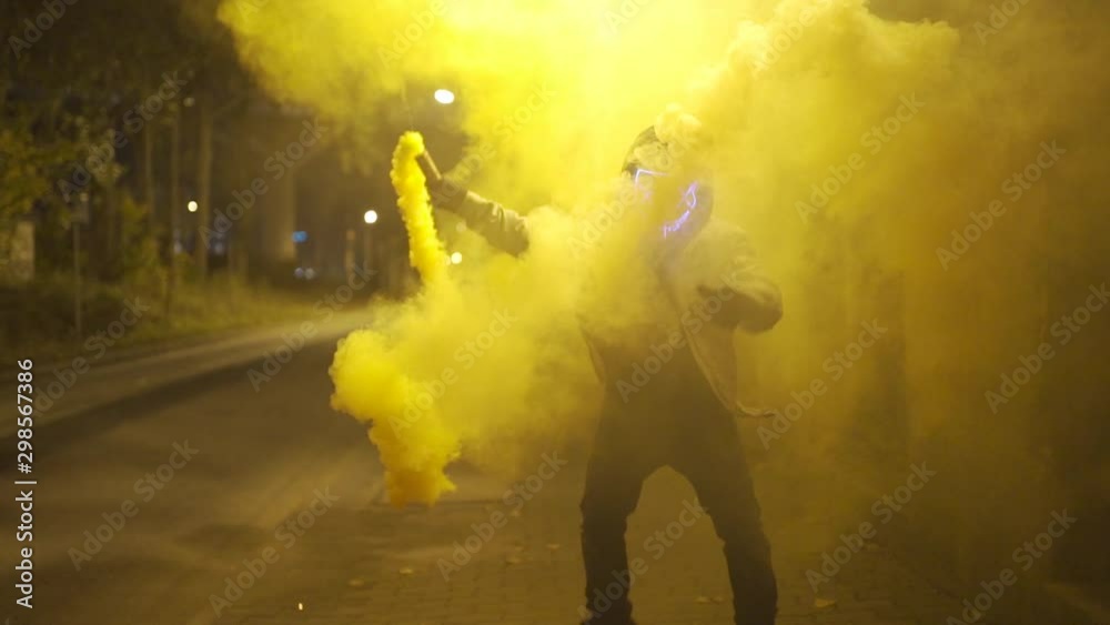 Man with purge mask and smoke grenade is dancing under a bridge at ...