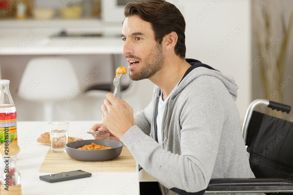 man eating a meal in his wheelchair Stock Photo | Adobe Stock