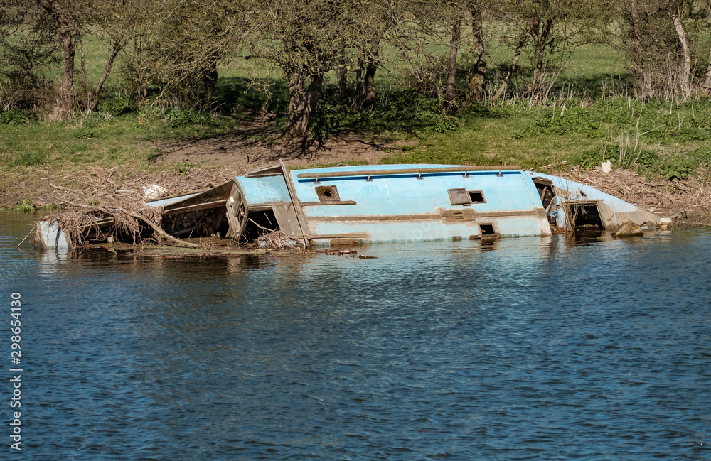 Wreck of a wooden barge seen decaying at the side of an inland waterway ...