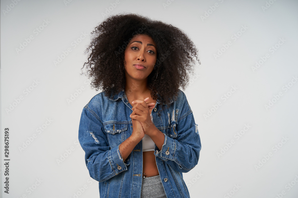 Portrait of young dark skinned lady with curly hair raising folded ...