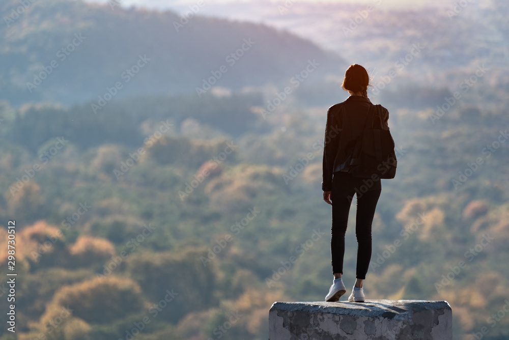 Girl stands on a hill and looks into the distance of the forest. Back ...