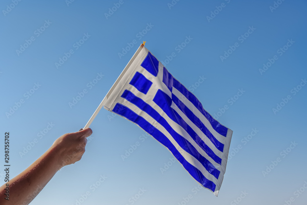 Hand waving Greek flag in the air for a national celebration. Blue ...