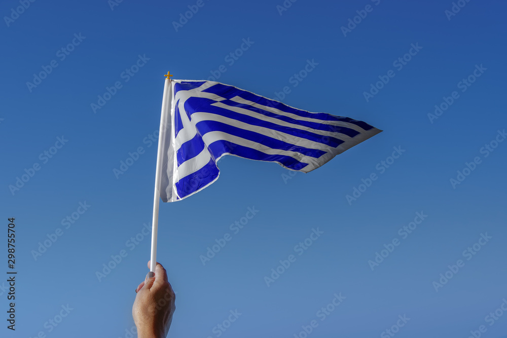 Hand waving Greek flag in the air for a national celebration. Blue ...