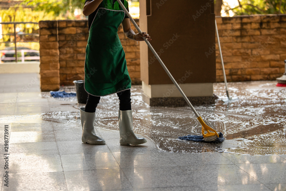cleaner with mop and uniform cleaning hall floor of public business ...