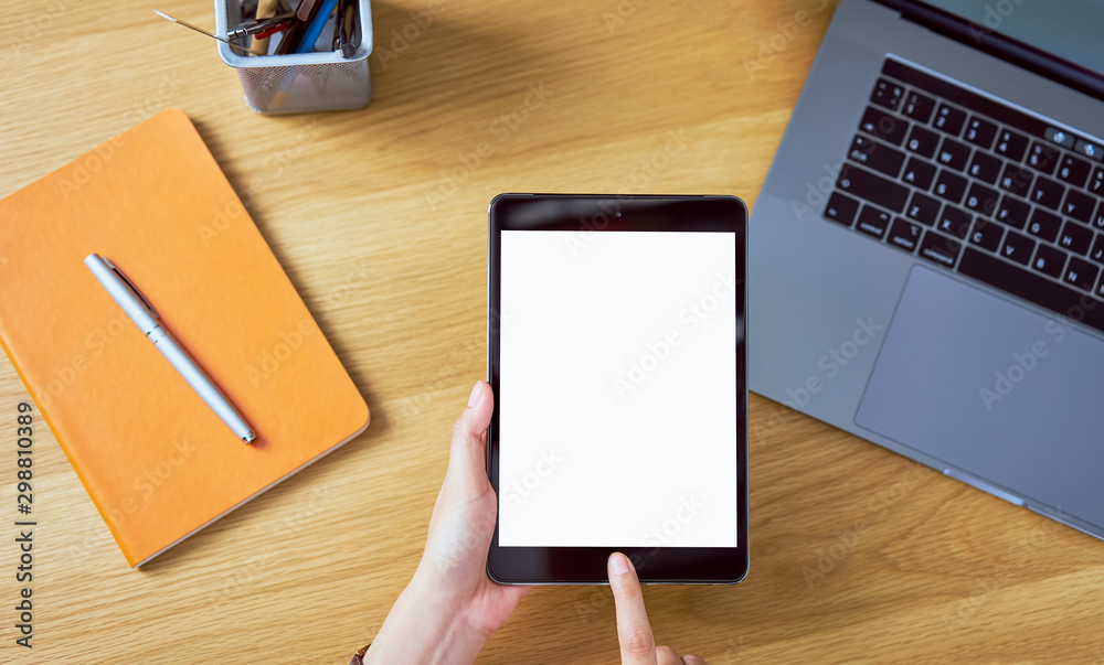 hands using tablet with blank screen with laptop and accessories on ...