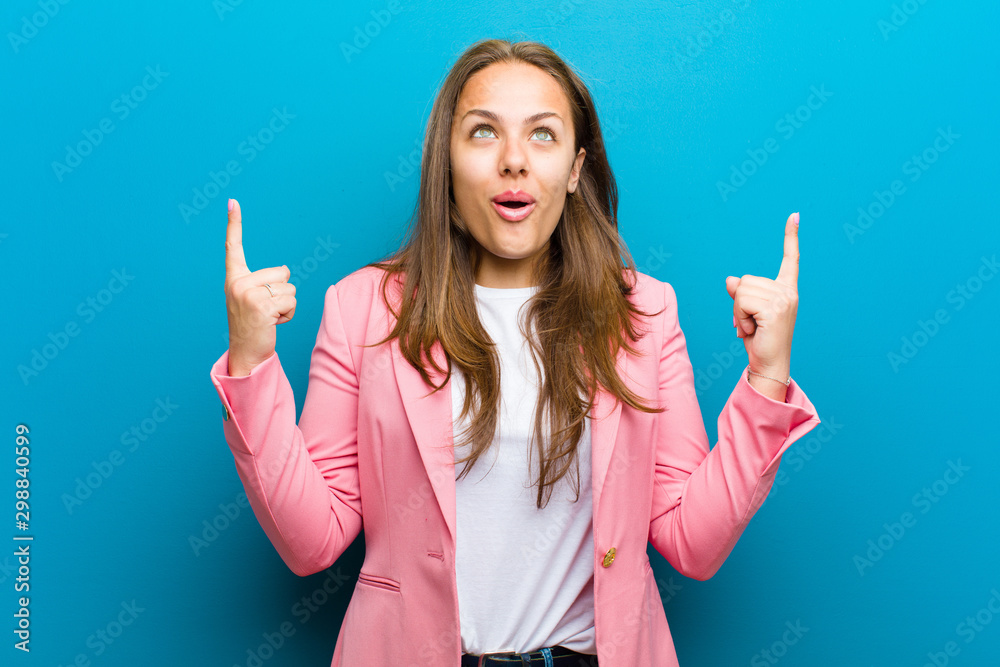 young woman feeling awed and open mouthed pointing upwards with a ...