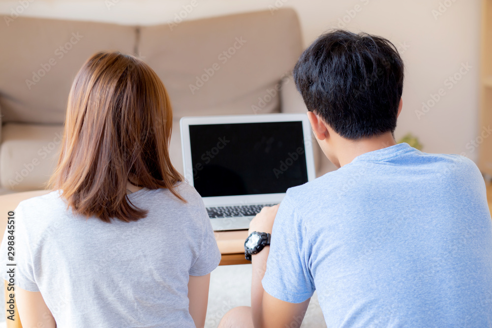 Back view of young asian couple working laptop with blank screen ...