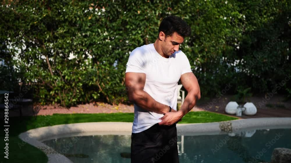 Attractive muscular young man undressing, taking off white t-shirt on ...