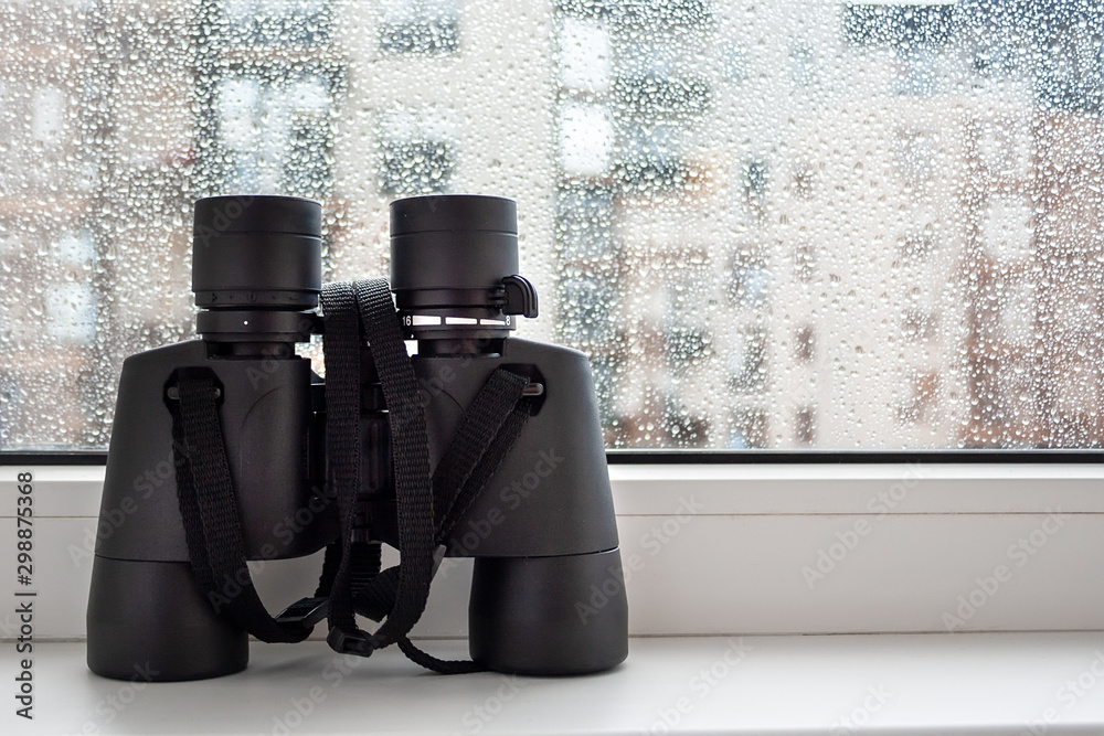 On a white windowsill by the window with raindrops on the glass is a ...