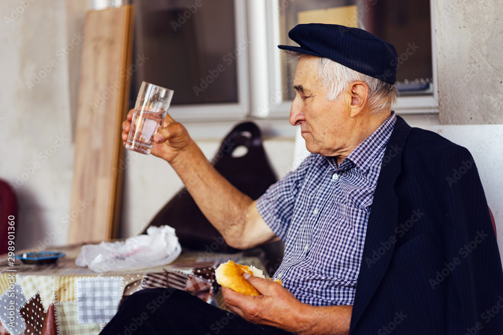 Senior old man pensioner drinking water while eating fast food burger ...