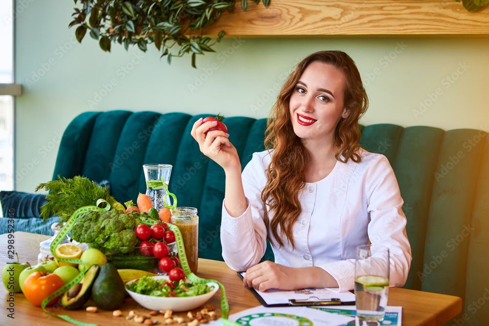 Woman dietitian in medical uniform with tape measure working on a diet ...