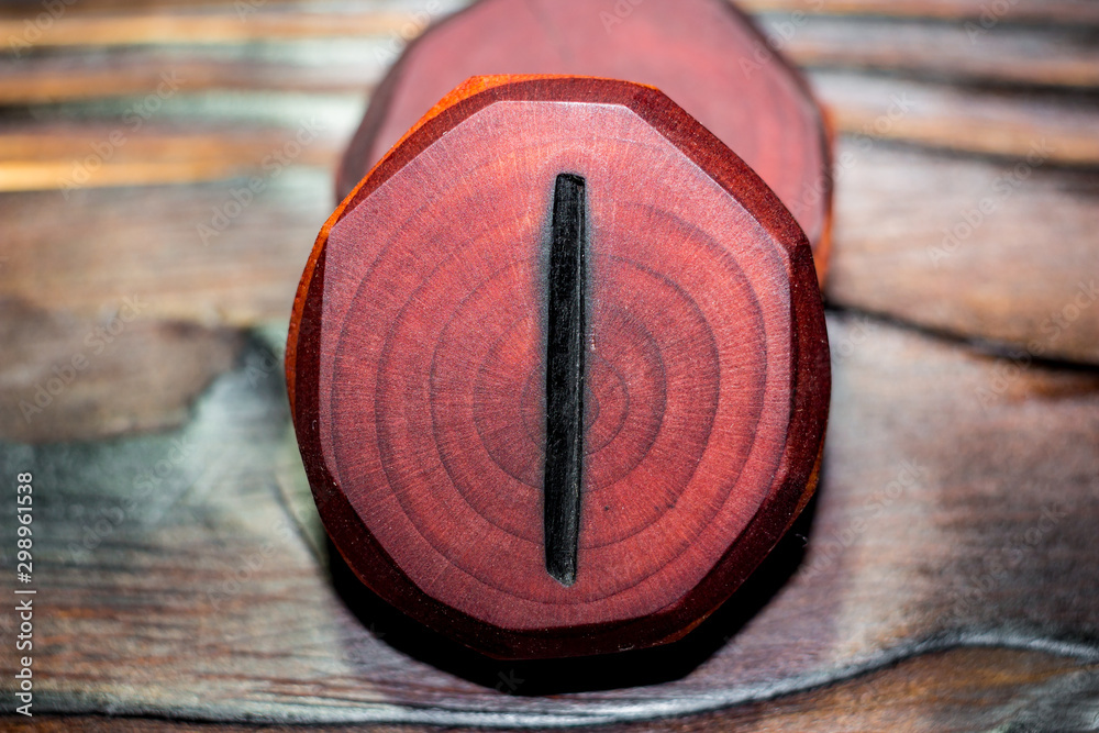 Rune Isaz (Isa) red color carved from wood on a wooden background ...