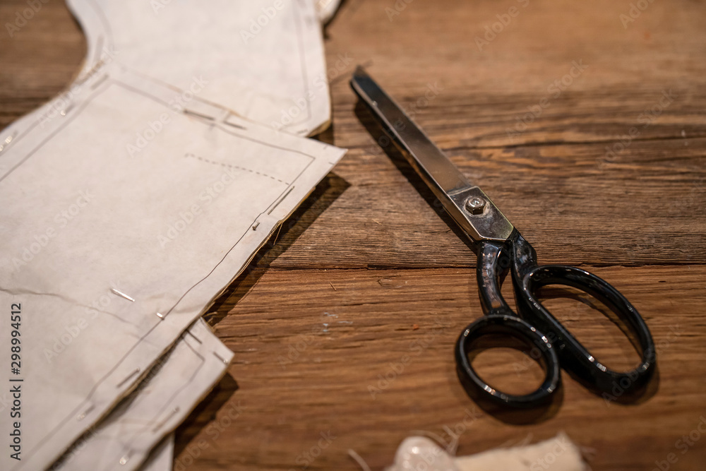 scissors, cutting paper pattern with light beige fabric. Close-up ...