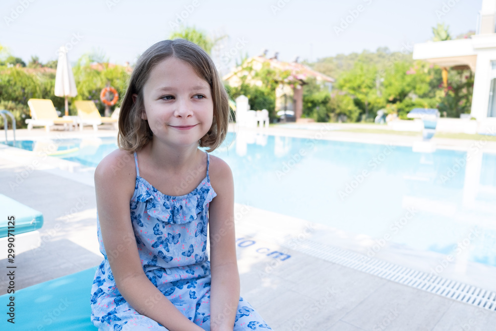girl sitting by the swimming pool on a lounger posing for a picture ...