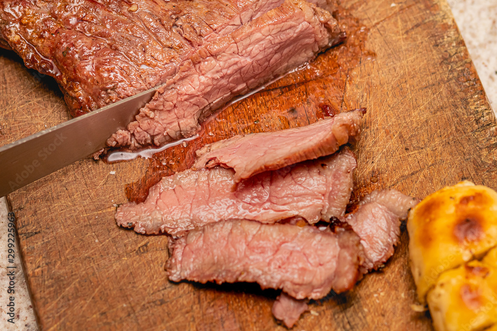 Churrasco brasileiro. Cortando a carne do churrasco sobre uma tábua ...