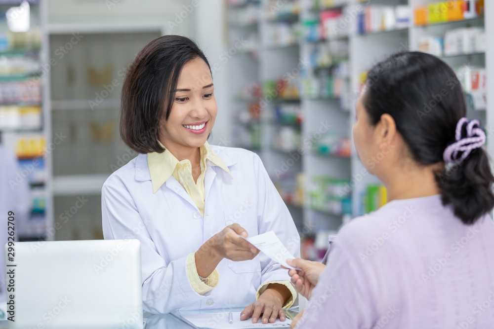 pharmacist asian woman received a piece of paper from a female patient ...