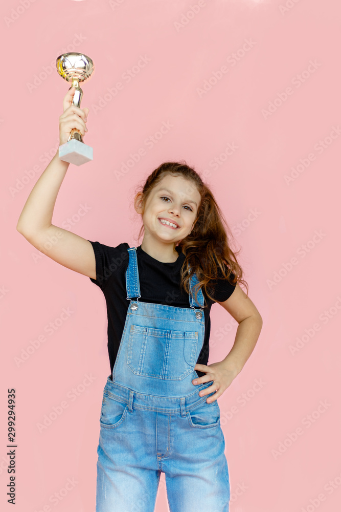 Happy little girl, smiling, showing a successful gesture of a winner ...