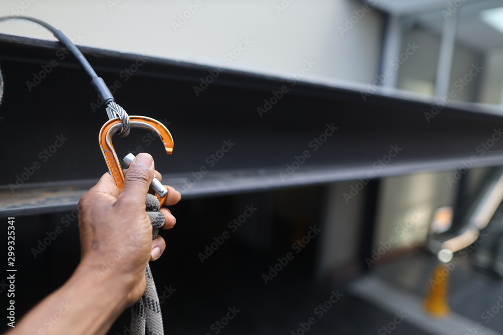 Rope access worker hand clipping locking Carabiner into first man up ...
