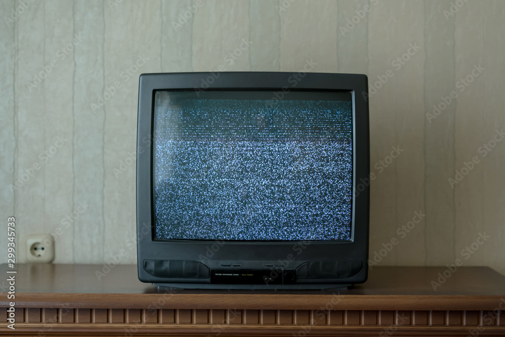 black old TV with static on screen standing on wooden table in room of ...
