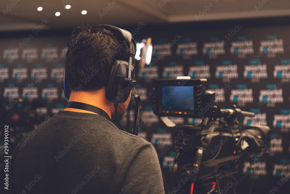 Video camera operator working with his equipment at indoor event ...